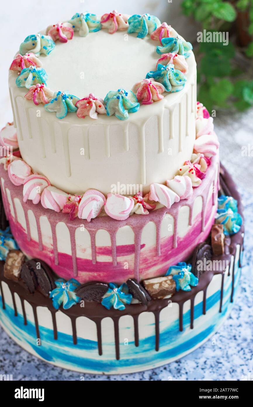 Three-tiered colored cake with colored smudges of chocolate on a light ...