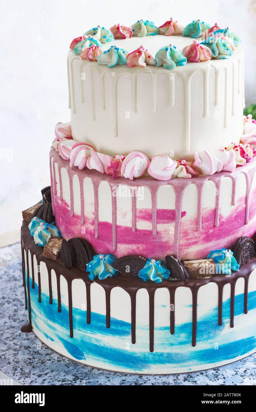 Three-tiered colored cake with colored smudges of chocolate on a light ...