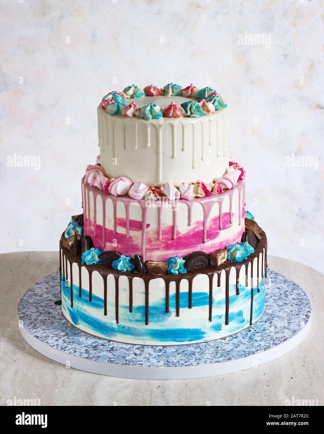 Three-tiered colored cake with colored smudges of chocolate on a light ...