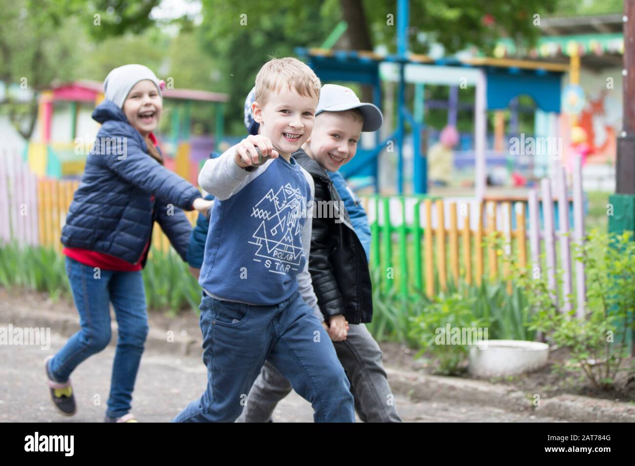 Happy preschoolers on the street. Children holding hands jumping Stock ...