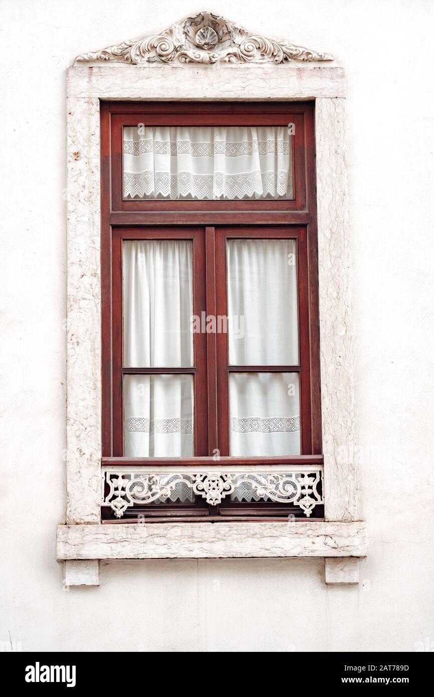 Ornate window with white moulding and lace curtains, typical of the ...