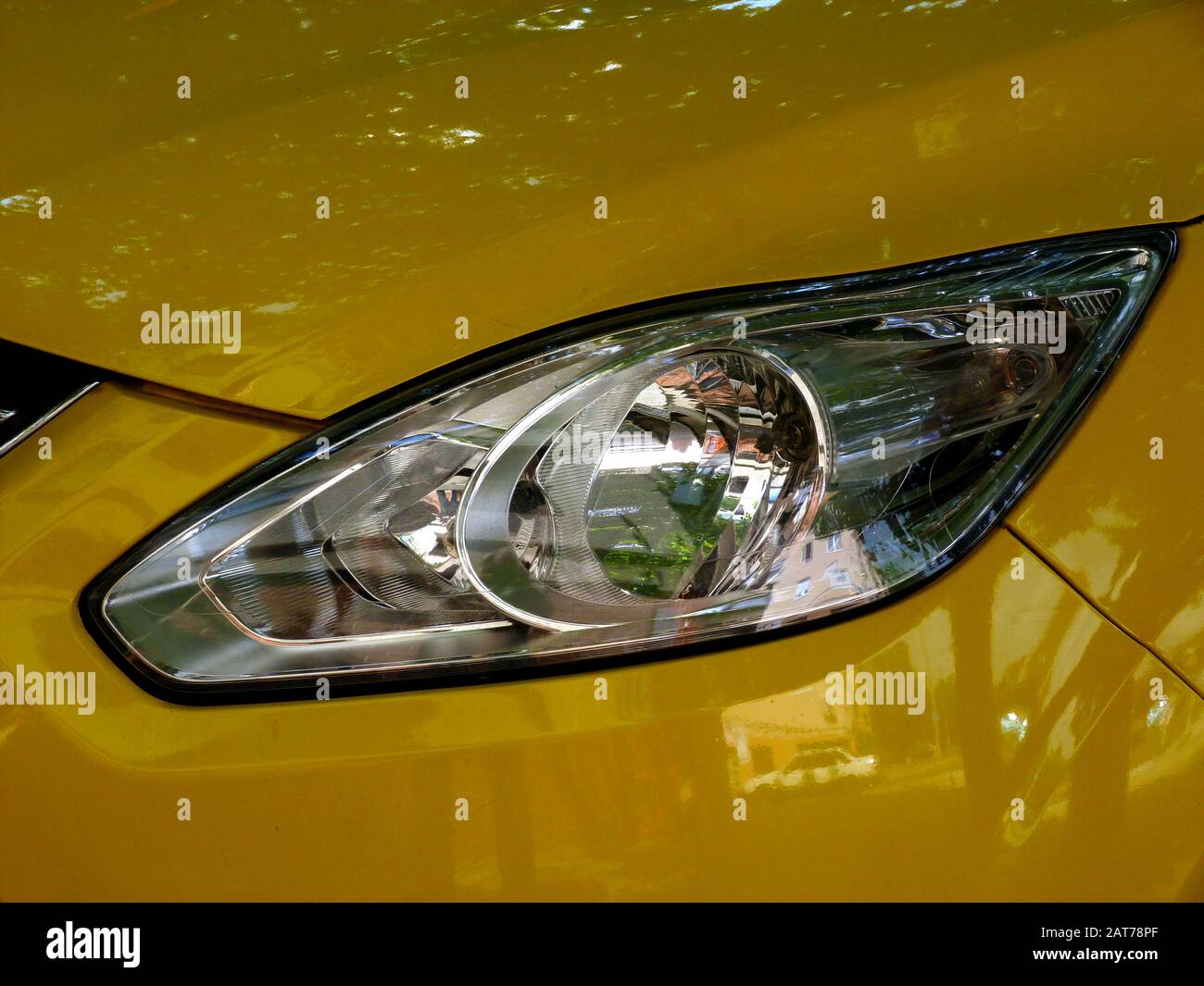 closeup of silver color plastic headlight lens. yellow color shiny car ...