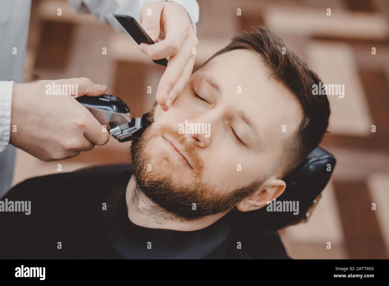 Barber shearing beard to man in barbershop framing hairline. electric ...