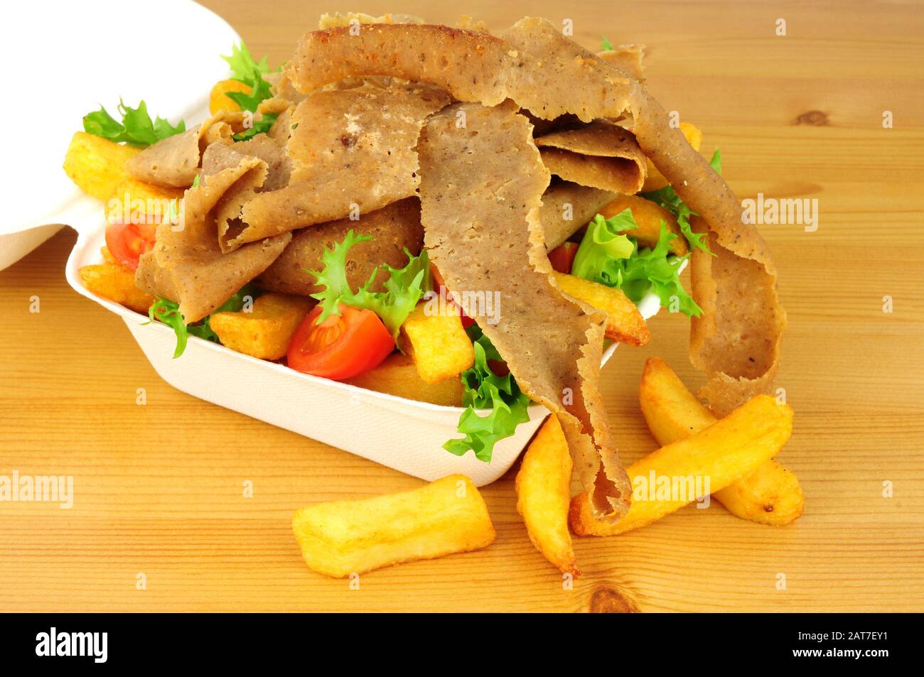 Take away kebab meat and chips with salad in an open fast food box ...