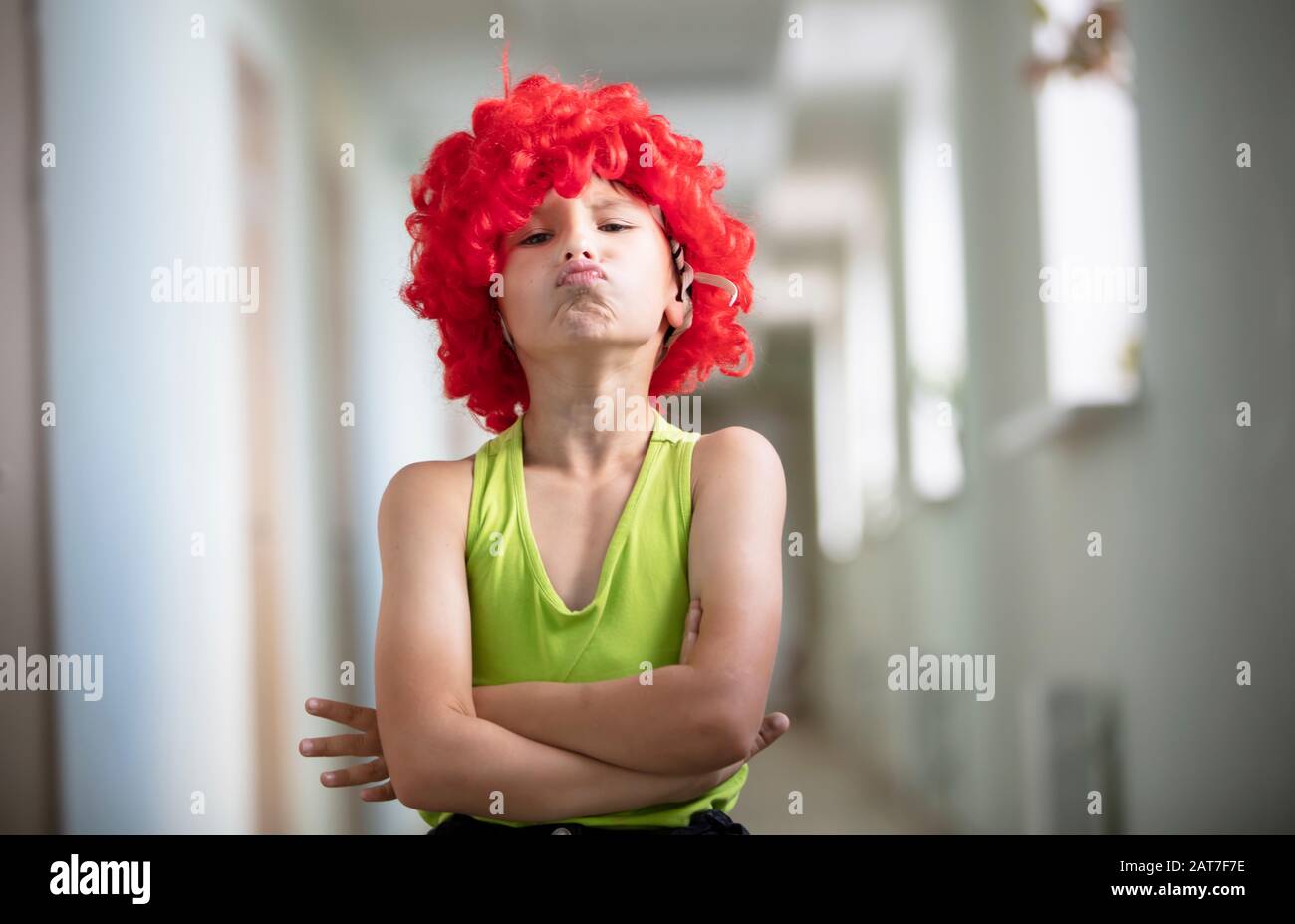 A child in a bright wig. Funny boy with red artificial hair. Artist ...