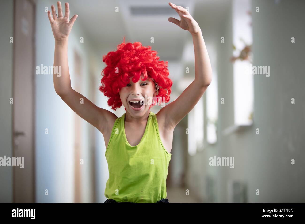 A child in a bright wig. Funny boy with red artificial hair. Artist ...