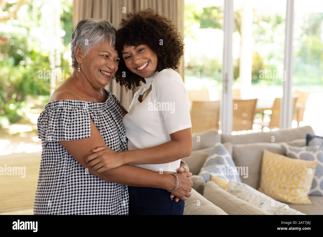 Two women smiling to each other at home Stock Photo - Alamy