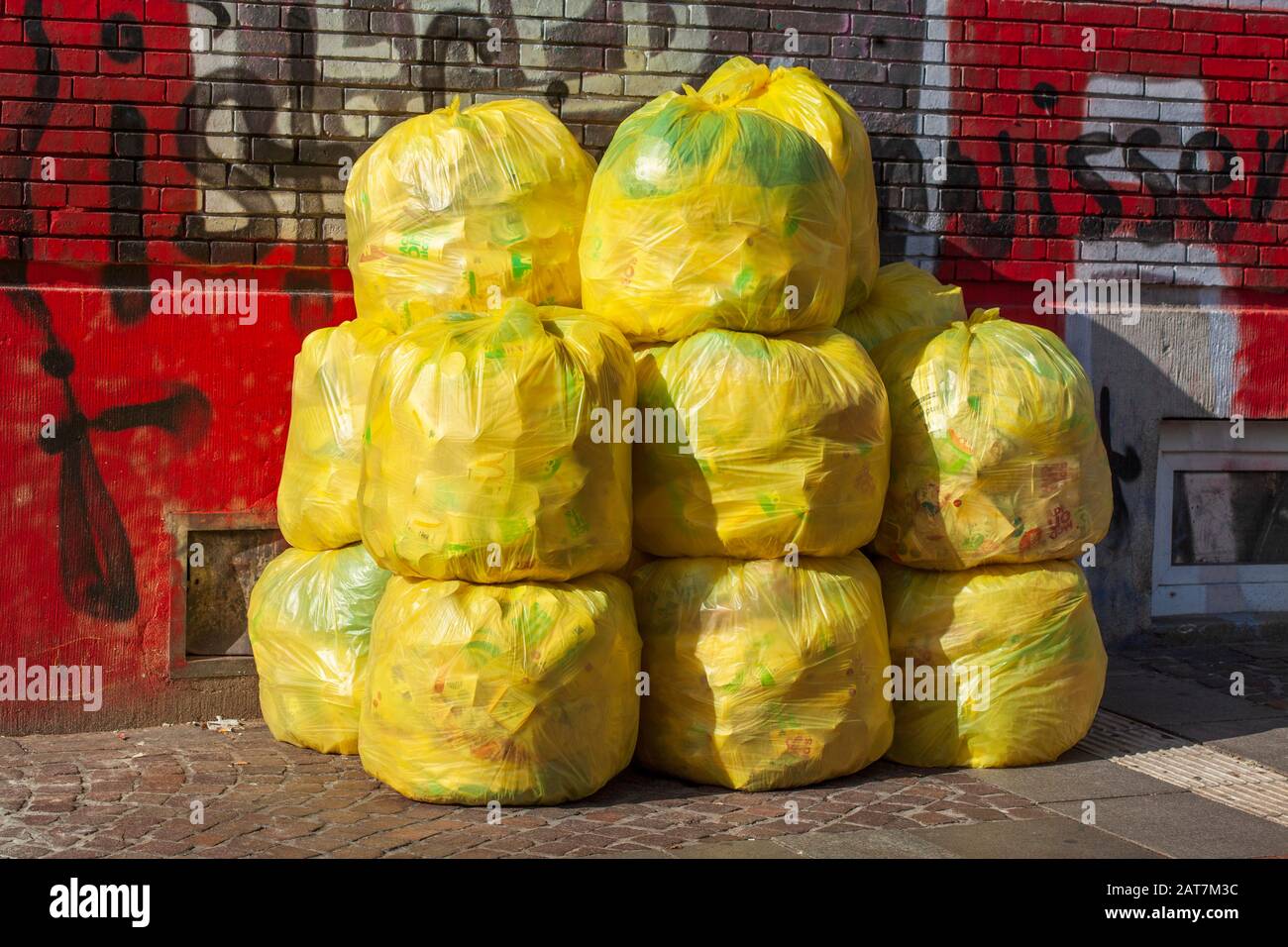 Stacked yellow bags for plastic waste in front of a house wall, Bremen ...