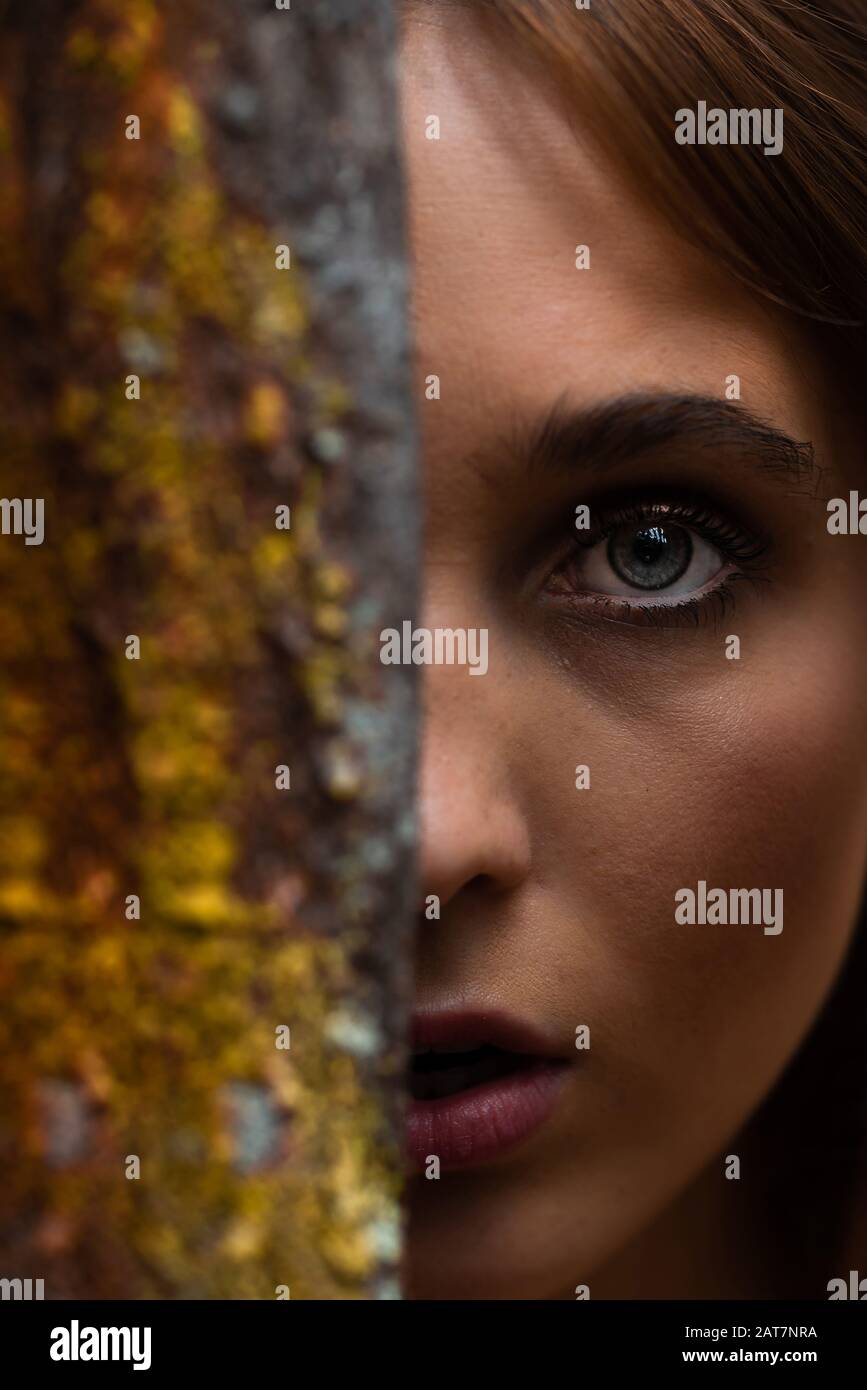Wild woman gazes behind tree Stock Photo - Alamy