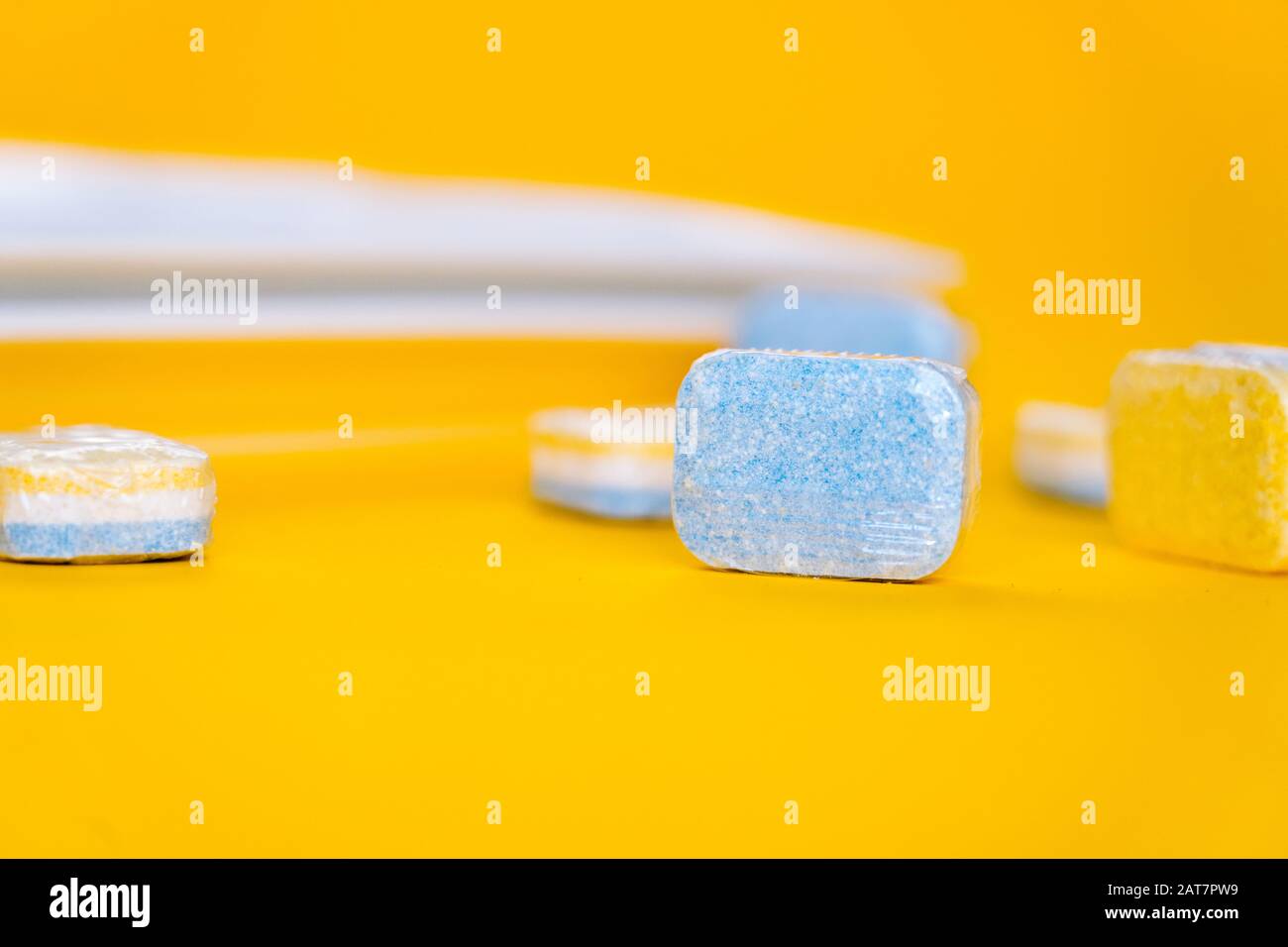 Cleaning dishwasher tablets on a yellow background. Group of bright colored soap tablet for ...