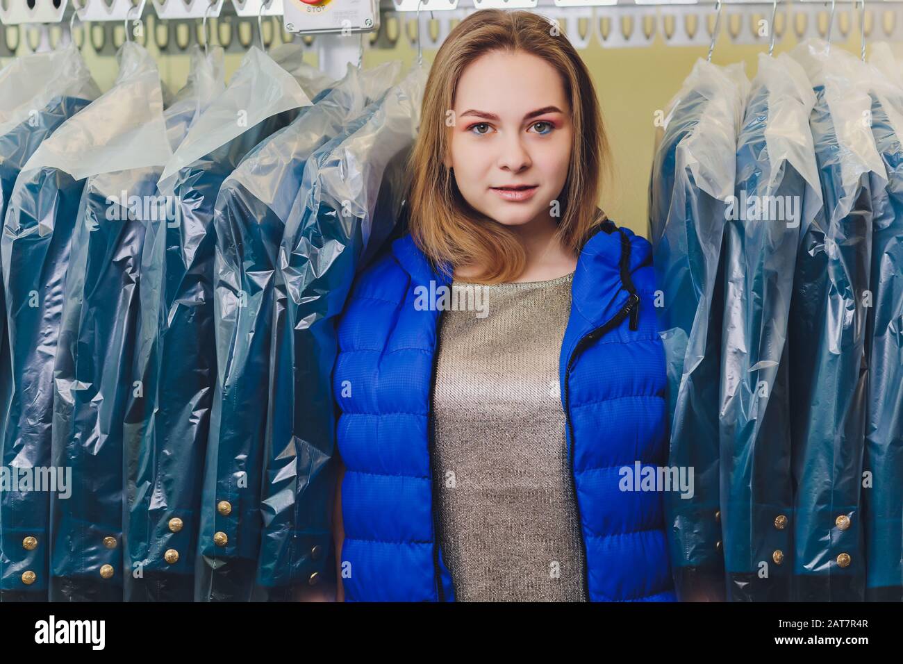Female cleaner in laundry shop or textile dry-cleaning next to clean ...