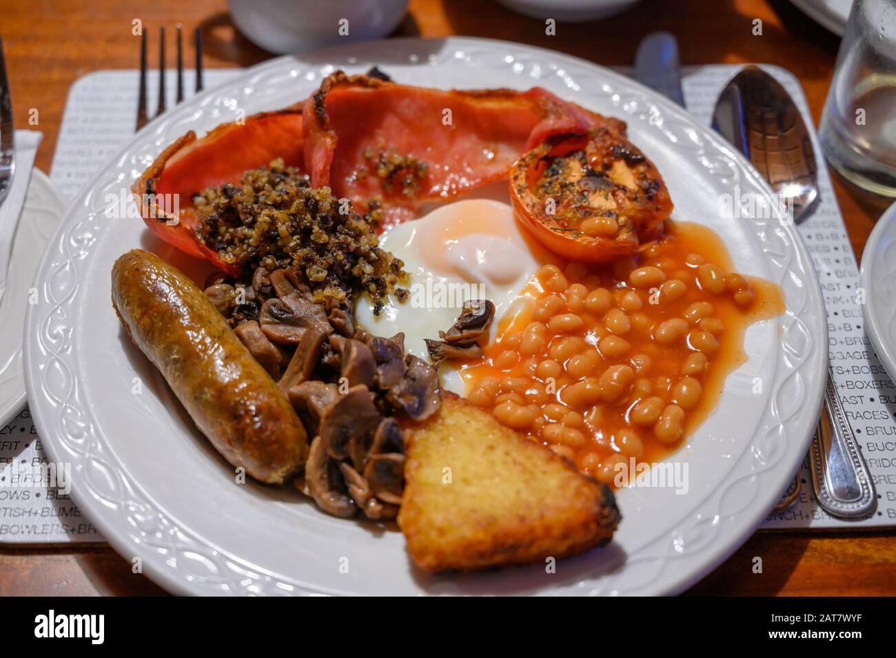White board with full Scottish breakfast with bacon, fried egg, beans, tomato, roasted sausage ...