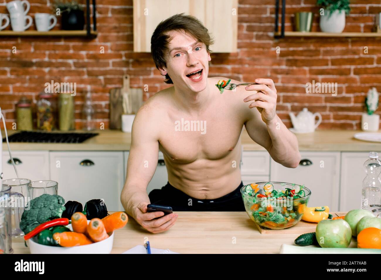 Close-up portrait of a handsome man eating salad with fresh vegetables ...