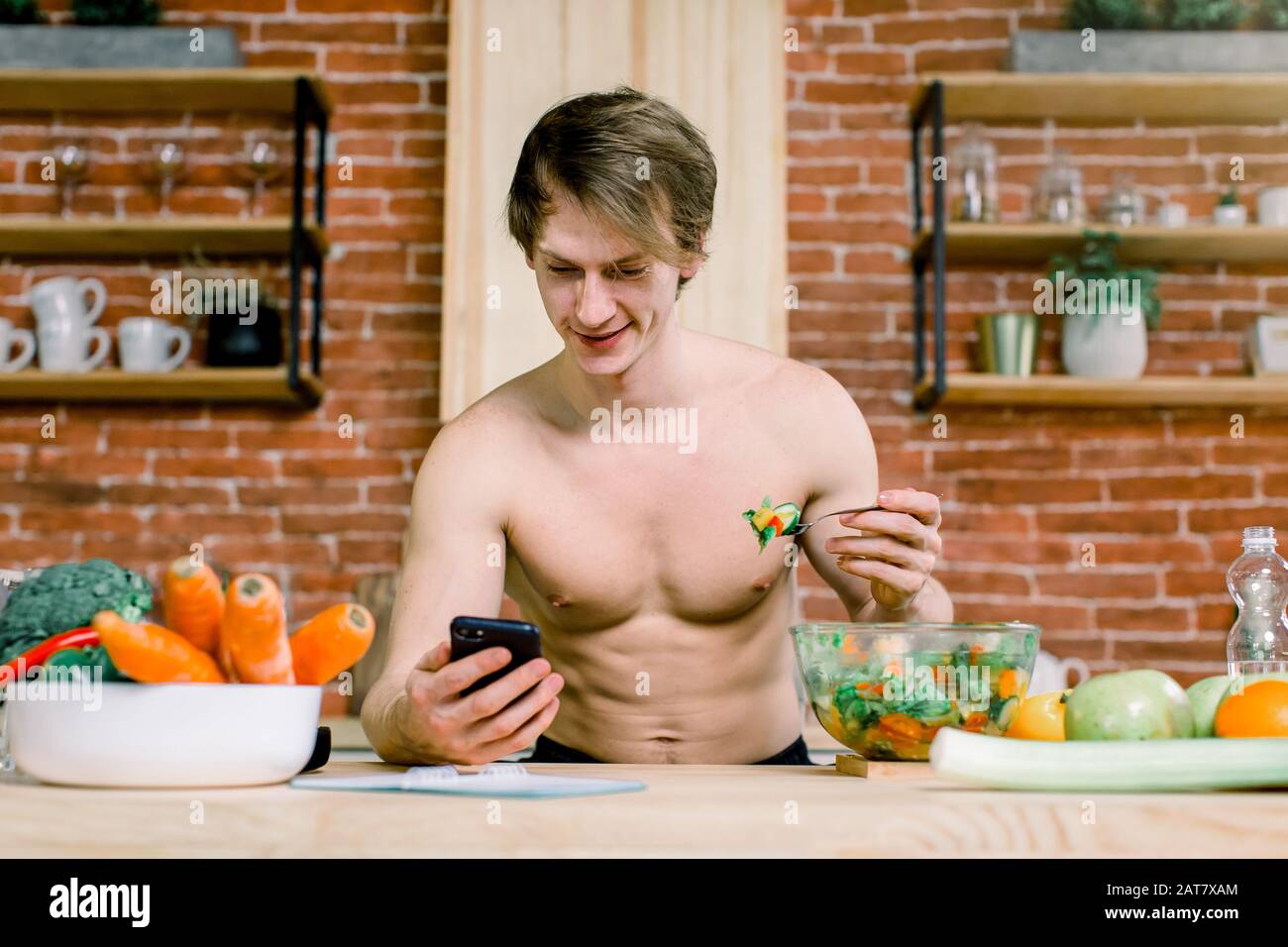 Close-up portrait of a handsome man eating salad with fresh vegetables ...