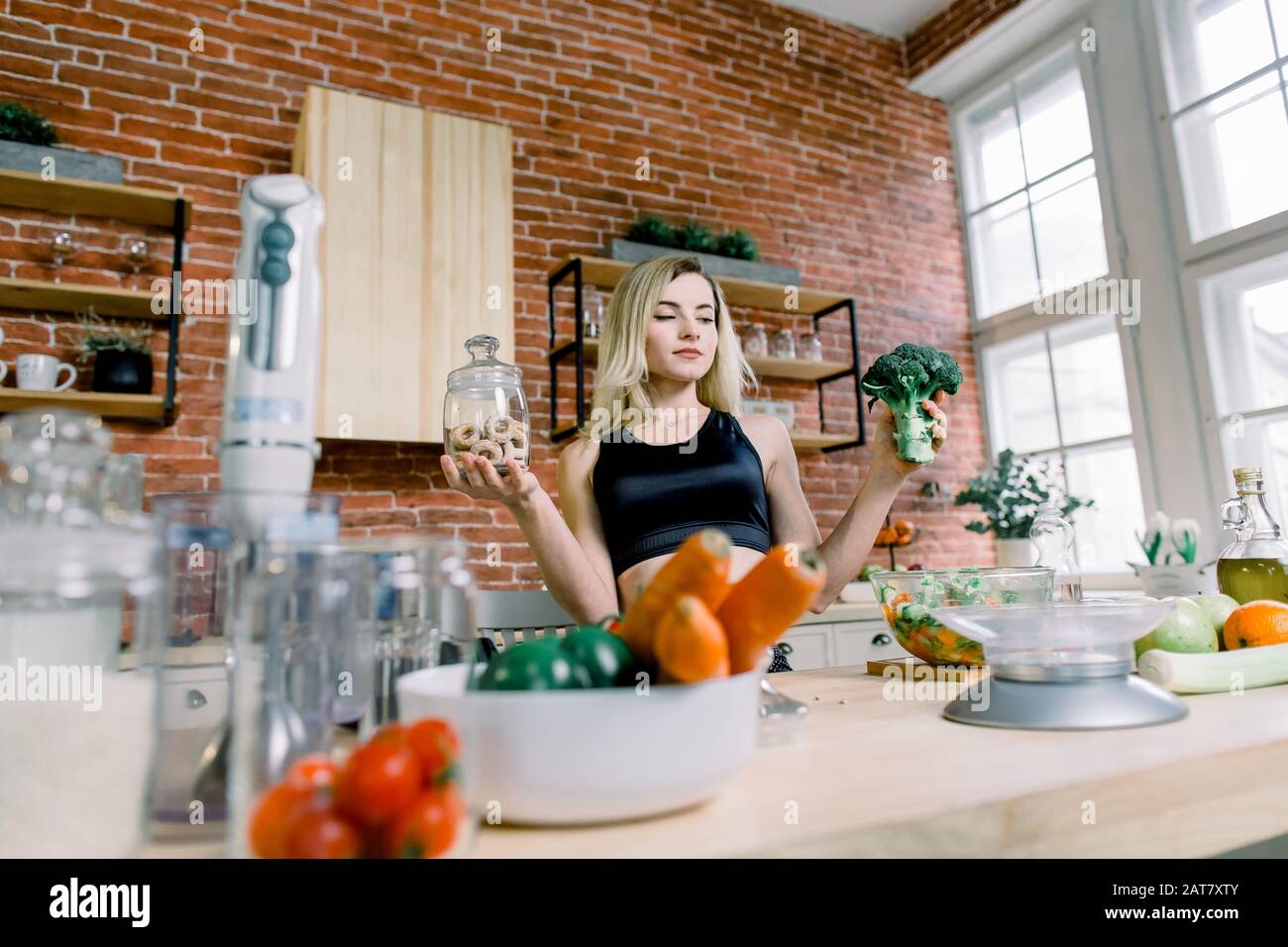 Young Caucasian blond woman having hard choice between healthy and ...