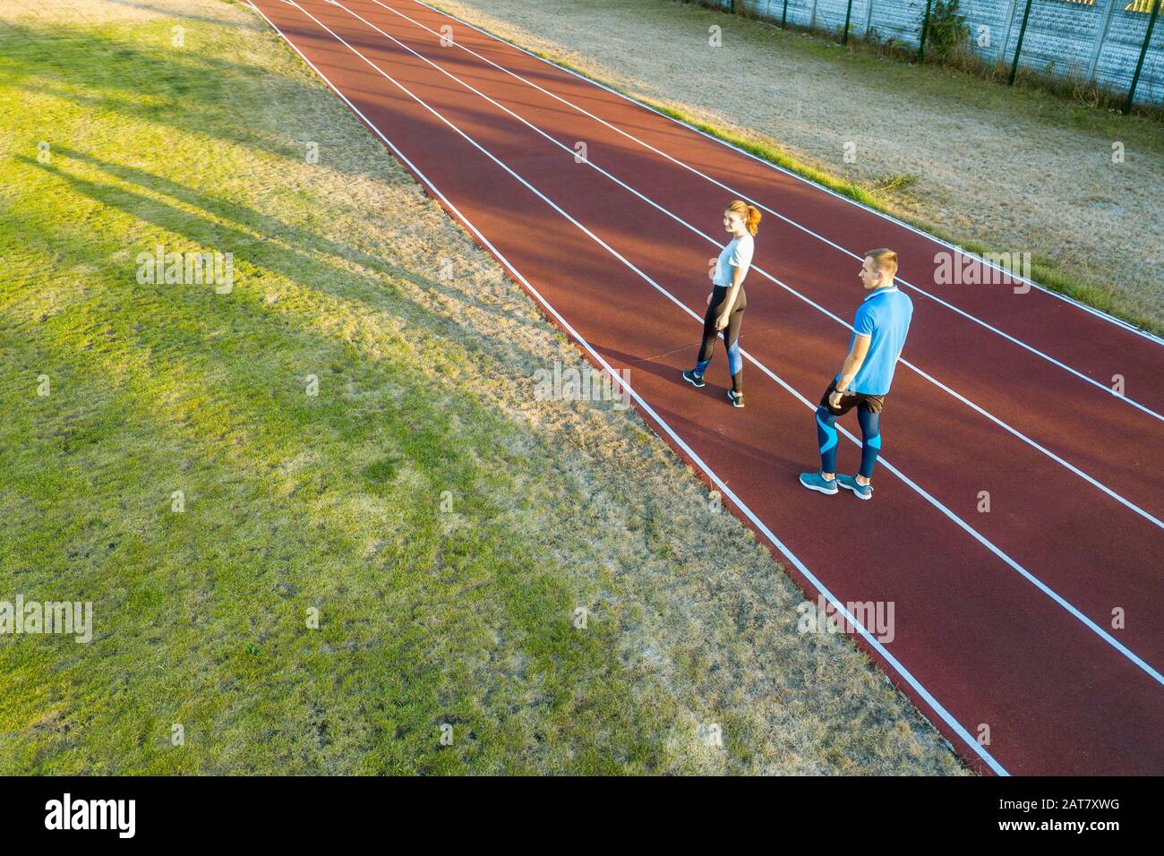 Top down aerial view of two young people sportsman and on red rubber ...