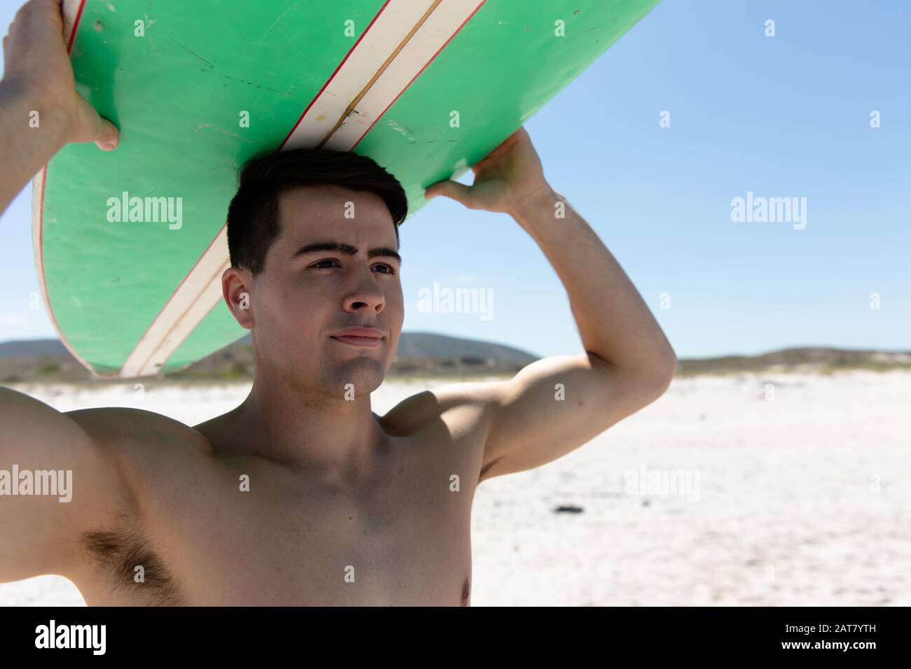 Young man carrying a surfboard at the beach Stock Photo - Alamy