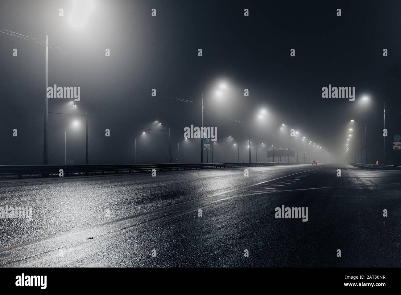 Foggy misty night road illuminated by street lights Stock Photo - Alamy