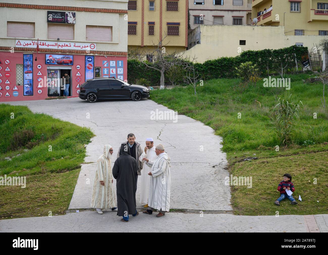 group of men having a chat in Tangiers, Morocco with child watching ...