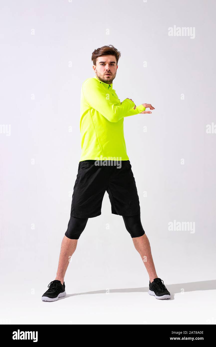 doing stretching first. young man in sportwear training and stretching ...