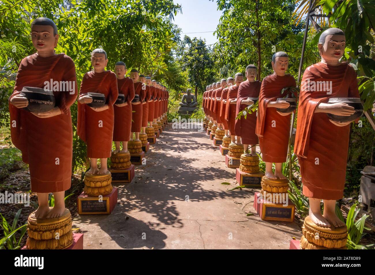 Row of Buddhist monk statues with red robes and alms bowls in the ...