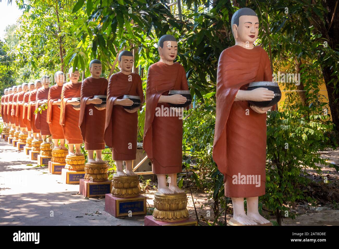 Row of Buddhist monk statues with red robes and alms bowls in the ...