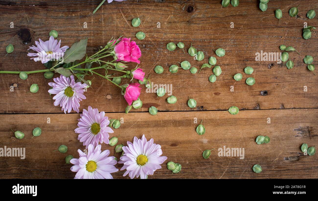 Spring flowers casually scattered on a rustic wood table background ...