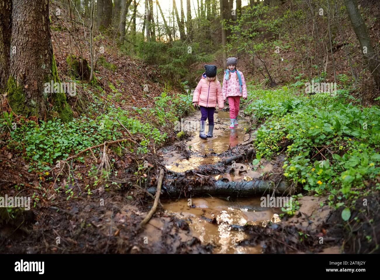Two cute young sisters having fun by a river on warm spring day ...