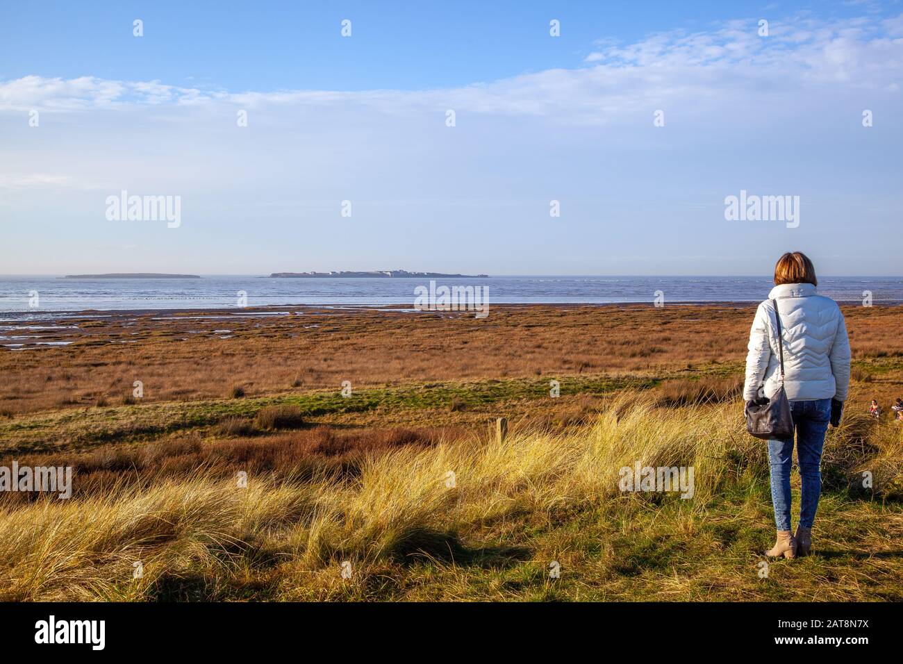 Woman walking along the coastal path along the river Dee through the ...