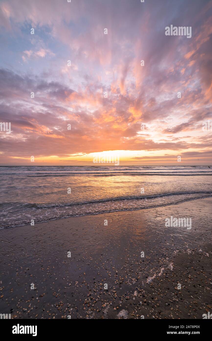 Colorful clouds at the dutch coast as the sun sets below the horizon ...