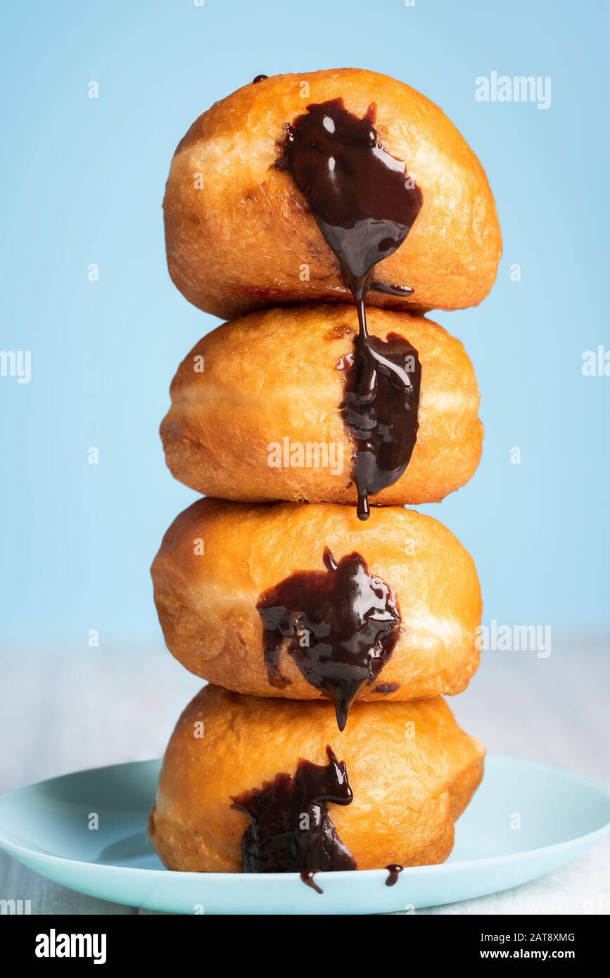 Homemade german doughnuts filled with melted chocolate stacked on a ...