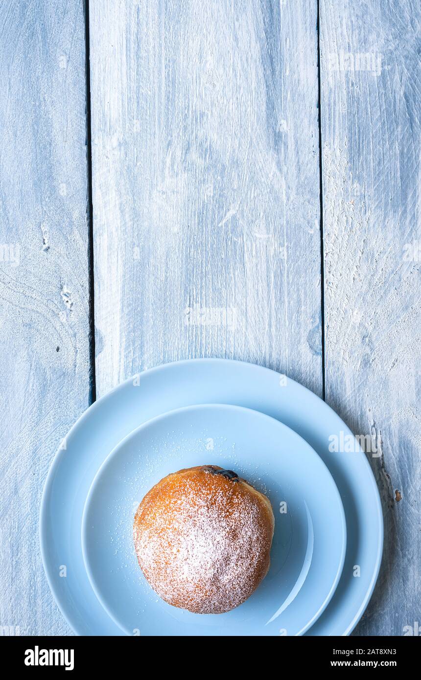 Single doughnut on two blue plates on a wooden table. Above view of ...