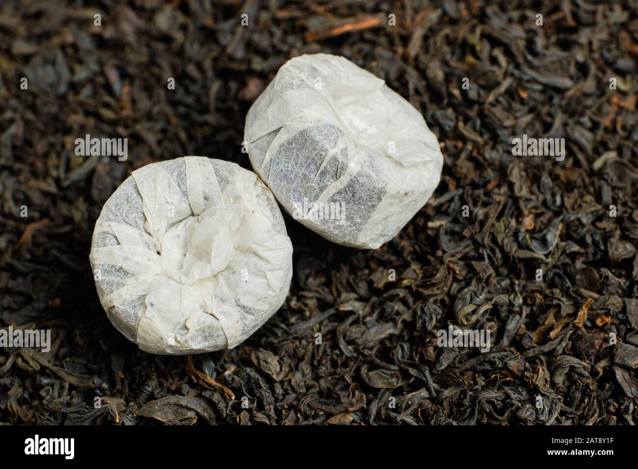 Two pressed tea tablets wrapped in white wrapping paper on background ...