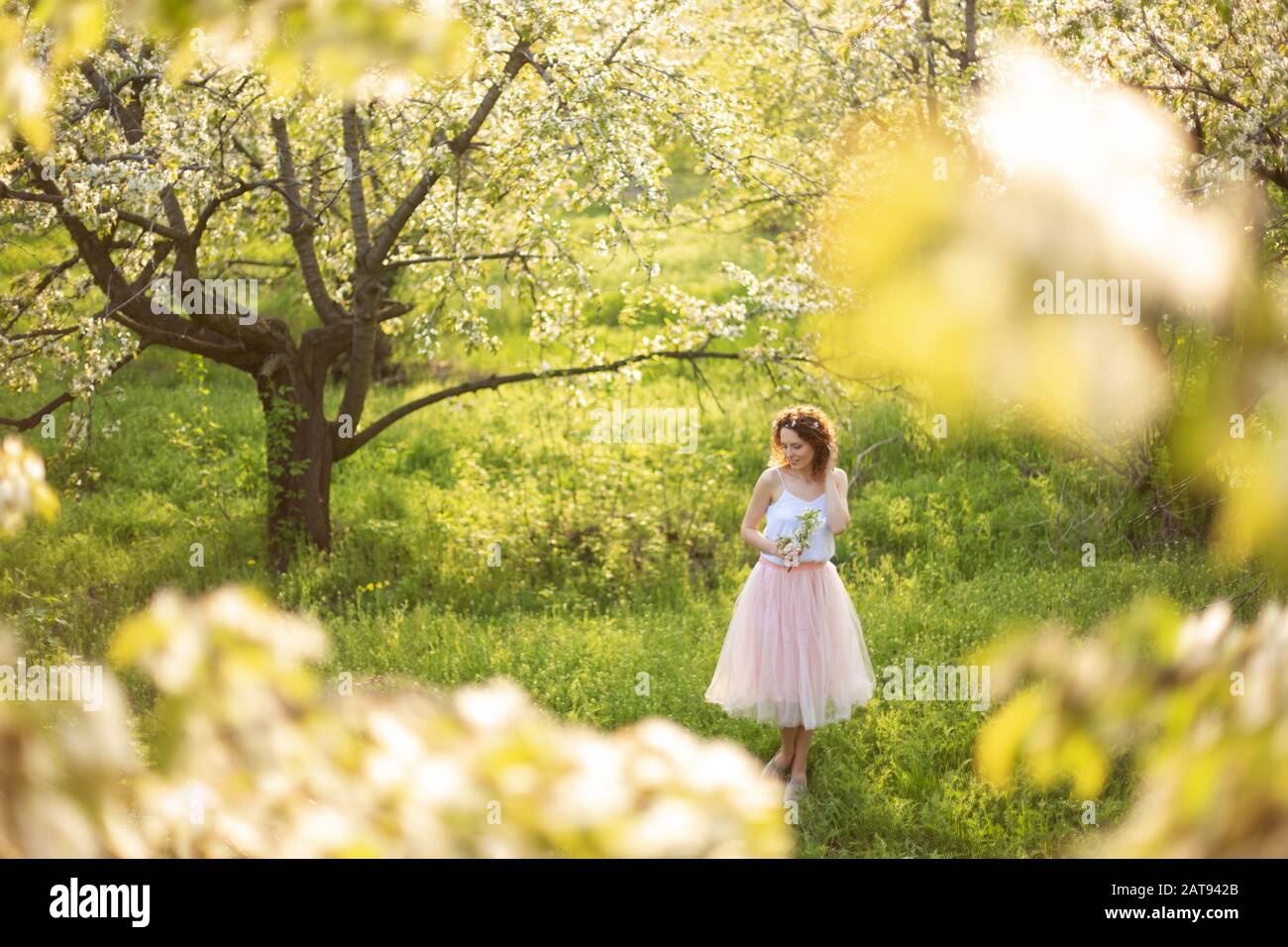 Young attractive girl walks in spring green park enjoying flowering ...