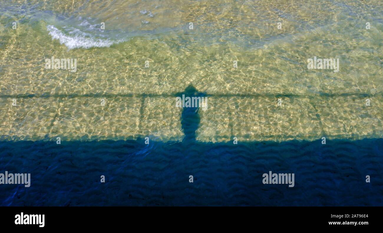 solitary silhouette of person looking over a bridge railing in to the ...
