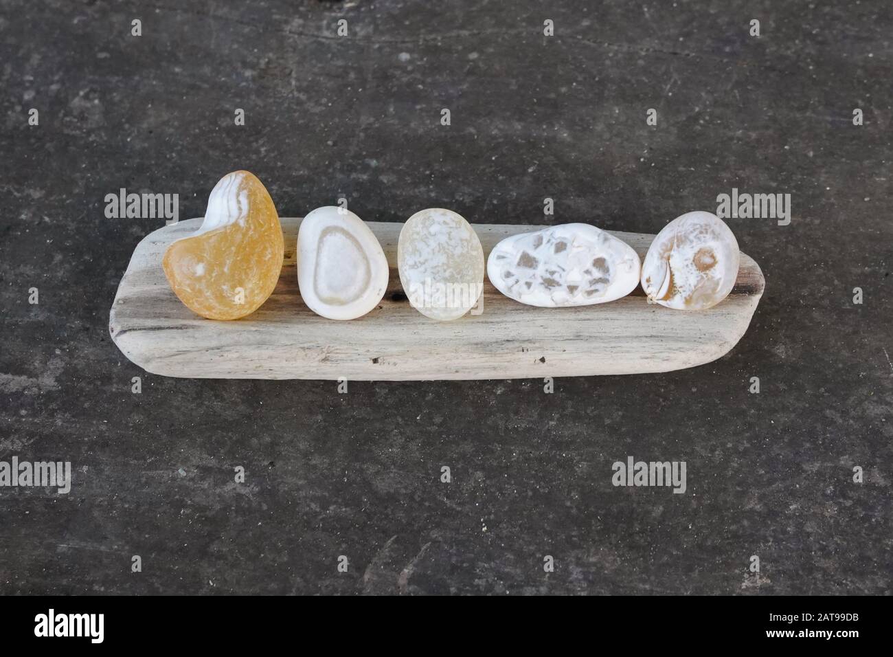 A collection of small agates lined up on a piece of driftwood Stock ...
