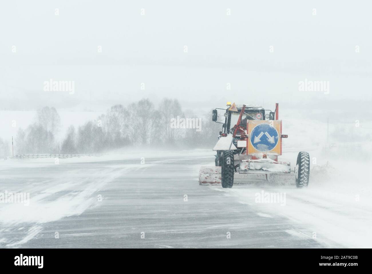 Snow removal machine on a snowy road background Stock Photo - Alamy