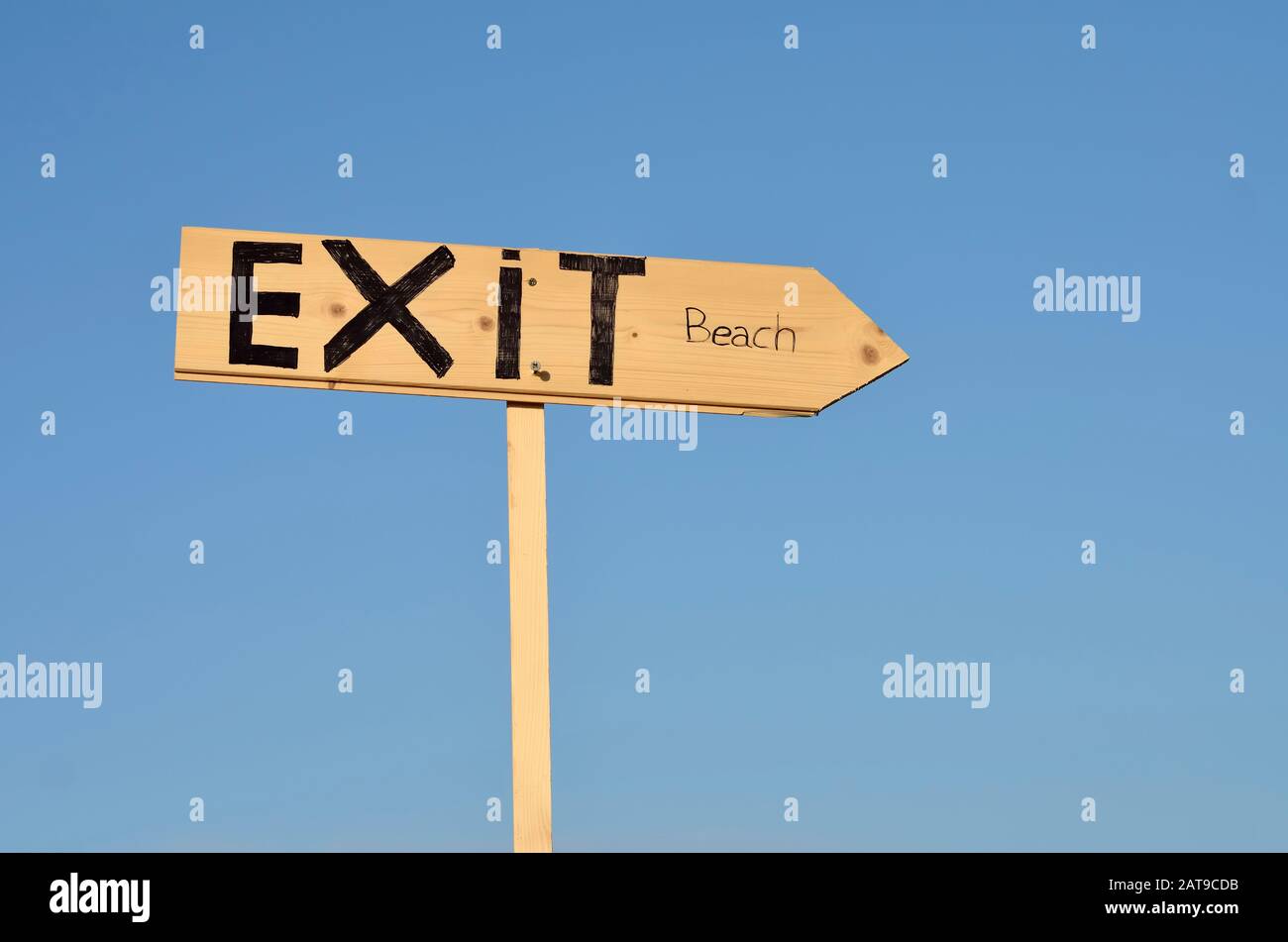 Wooden arrow sign with the word exit. In the background the blue sky ...