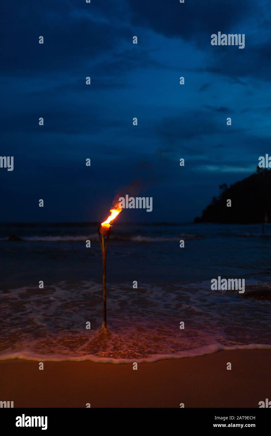Burning torch on the sandy beach of the ocean Stock Photo - Alamy