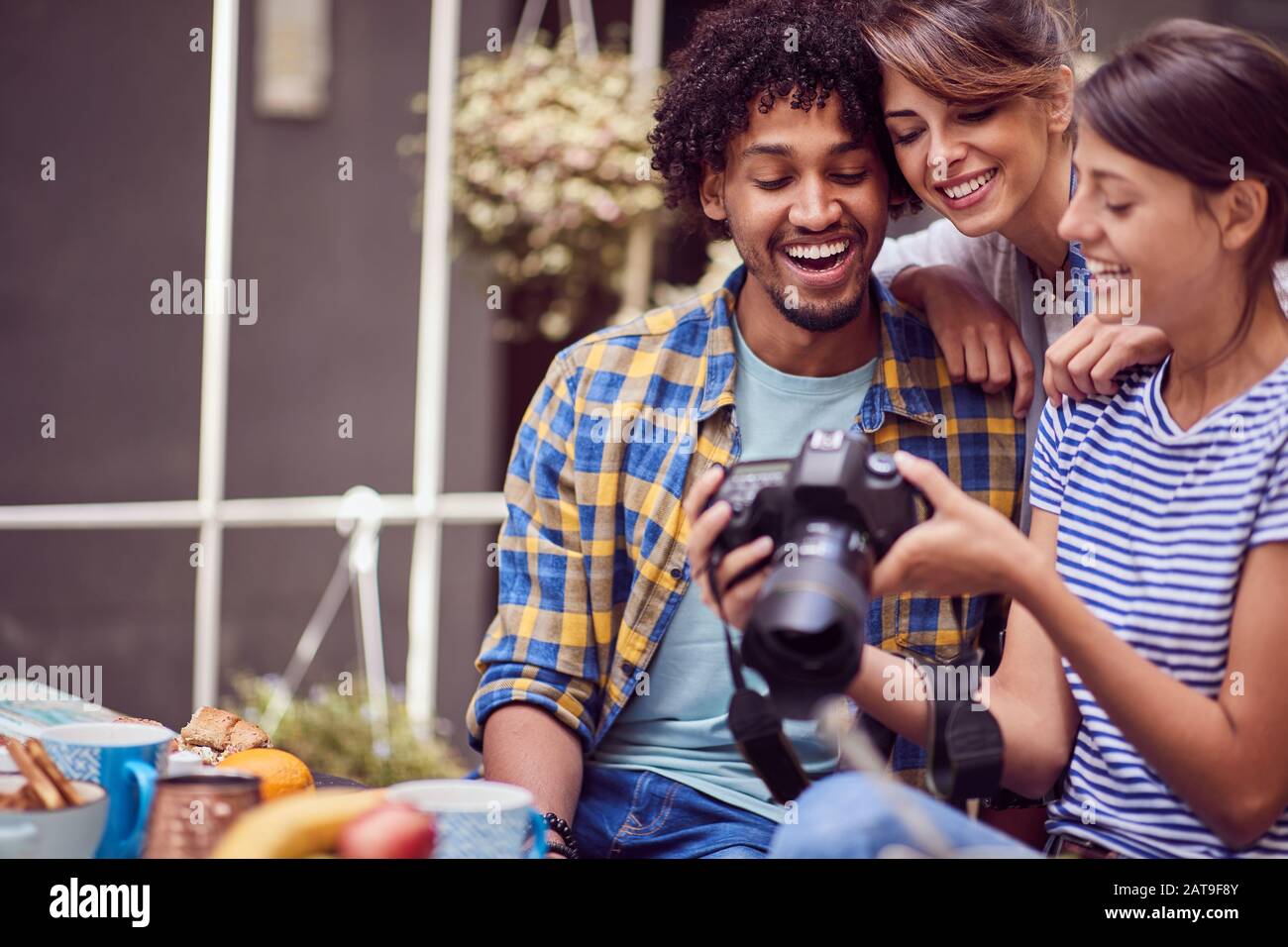 group of young smiling friends looking to camera and talking about ...
