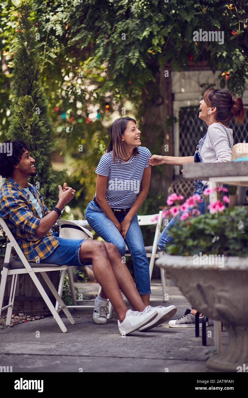group of smiling young friends talking outdoor in nature while having a ...