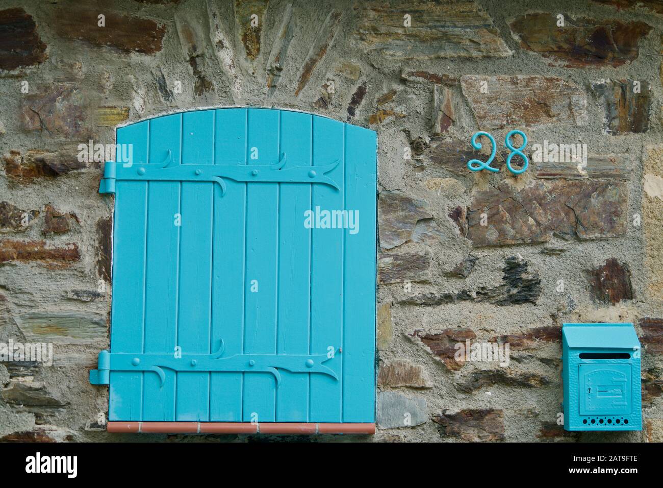 Turquoise folding shutter and letter box in a natural stone wall Stock ...