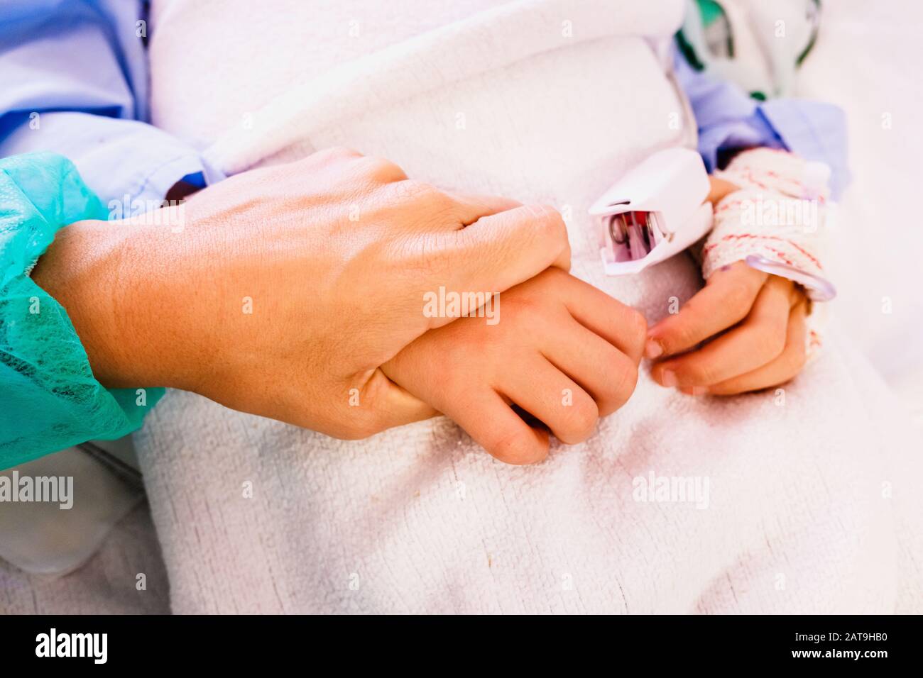 Mother holds her son's hand to encourage her in a hospital bed before ...