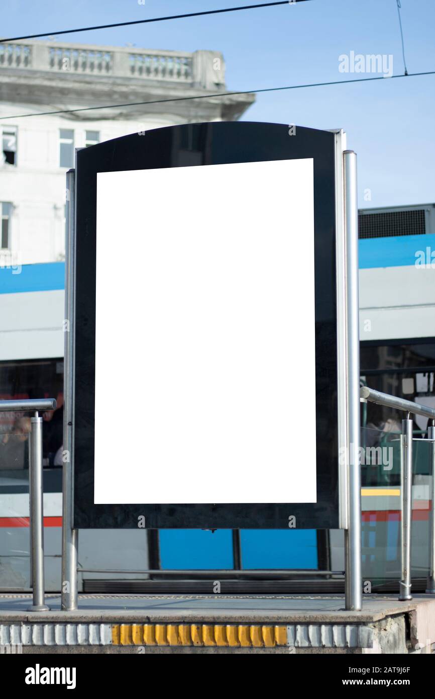 Advertising sign at the tram station stop. The tram passes in the ...