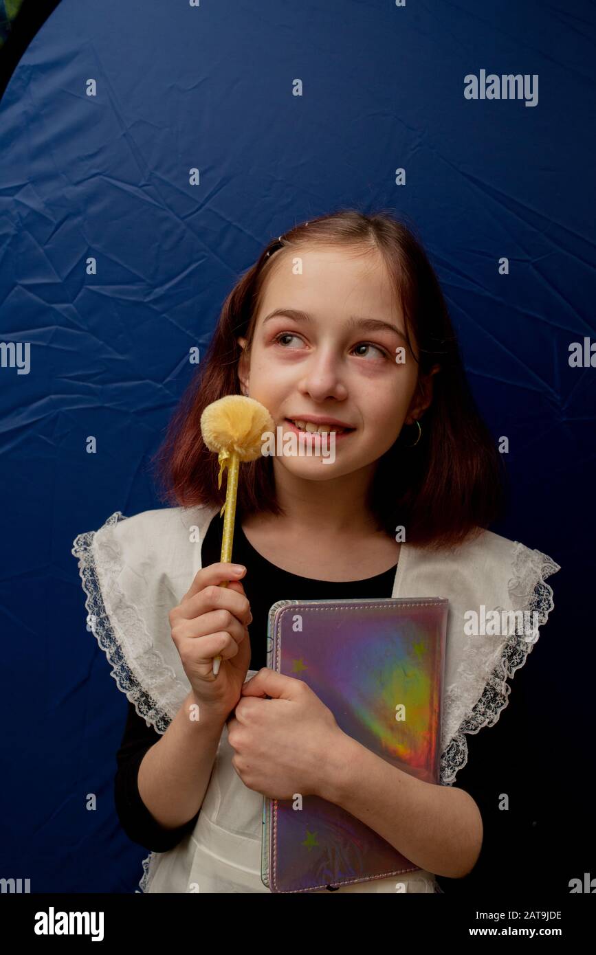 portrait of sweet honor schoolgirl in shirt on the blue background ...