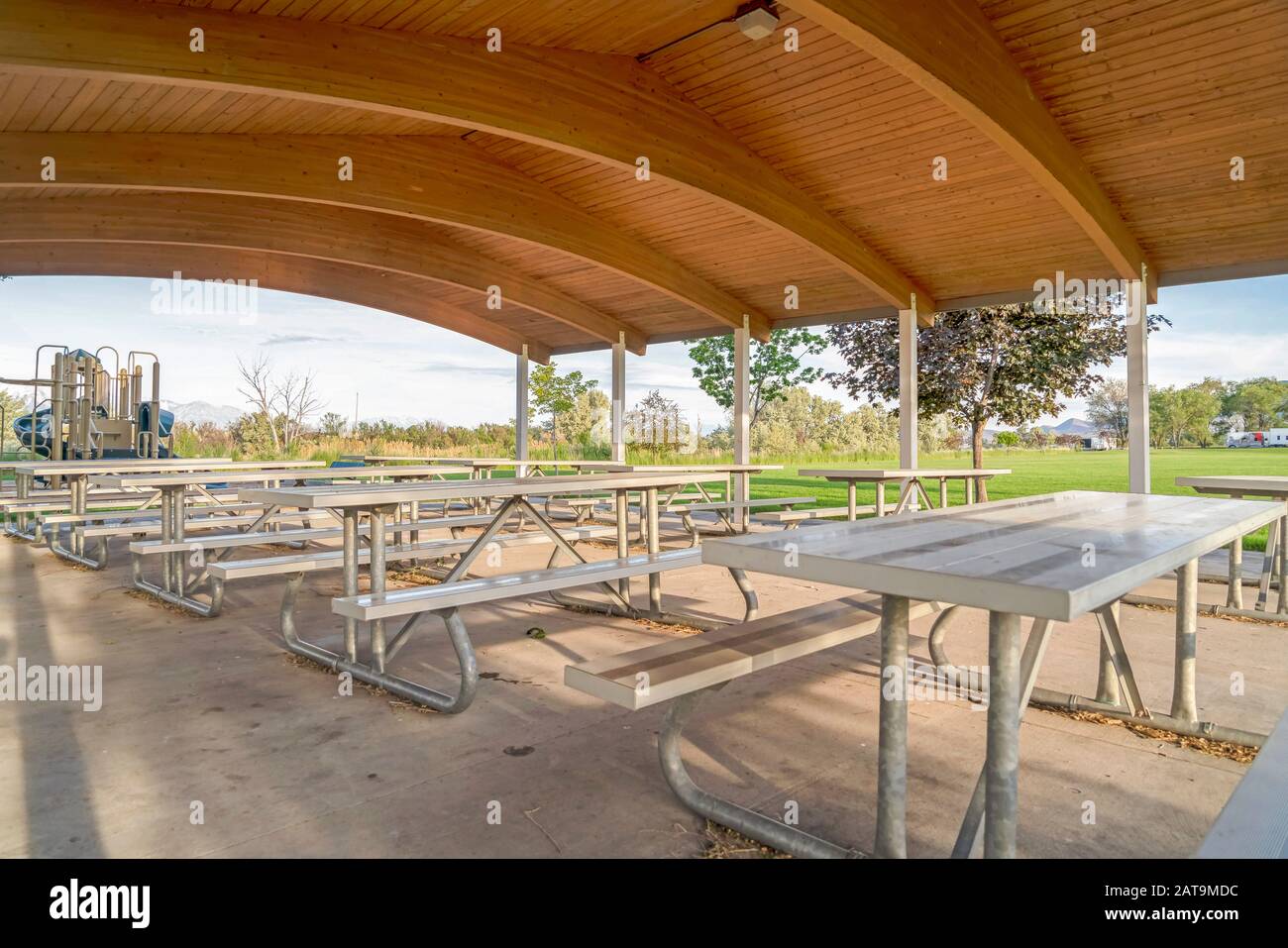 Eating area at a park with tables and seats under brown wood roof of ...