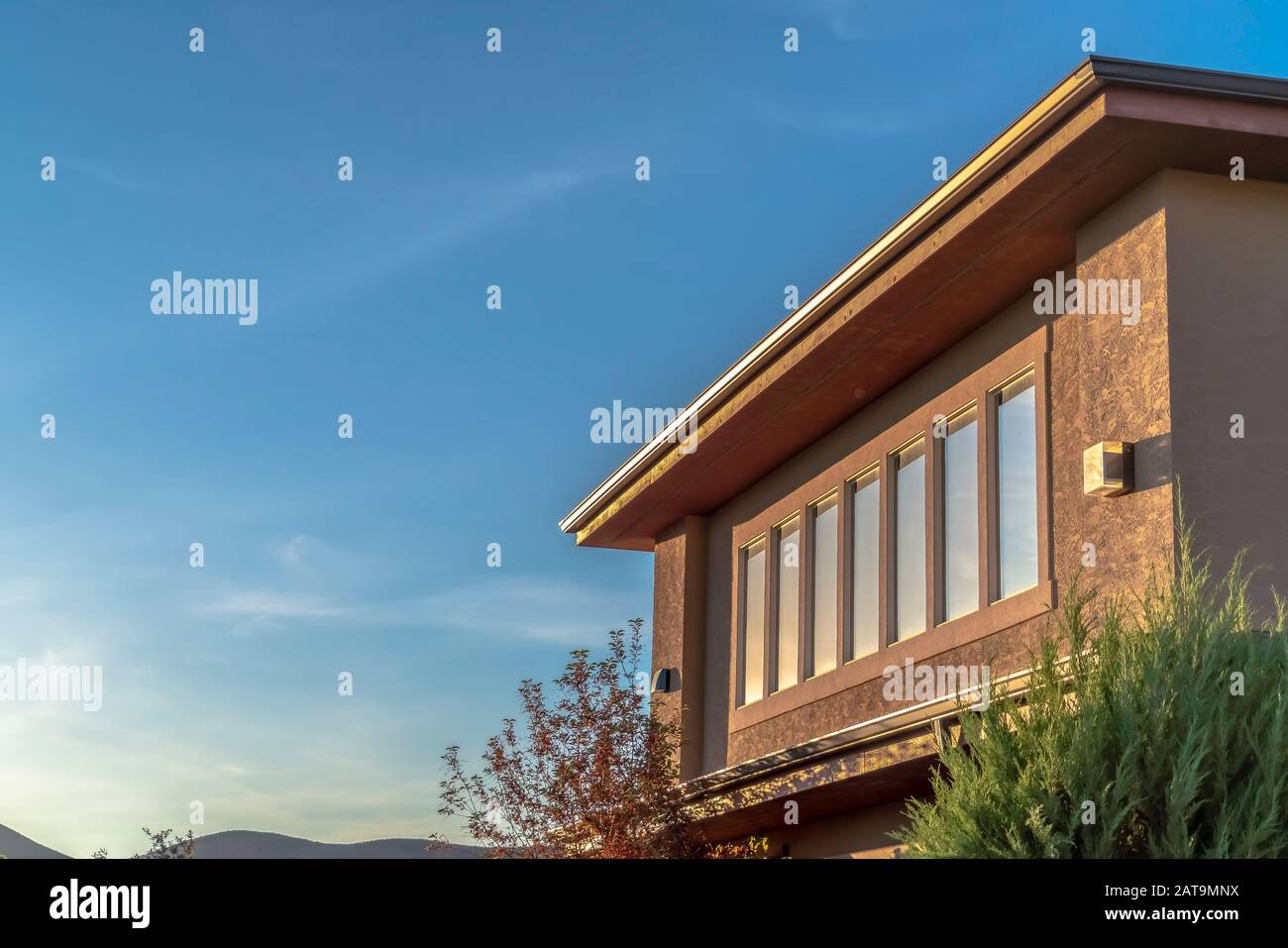 Sunlit house exterior with view of the upper storey against mountain ...