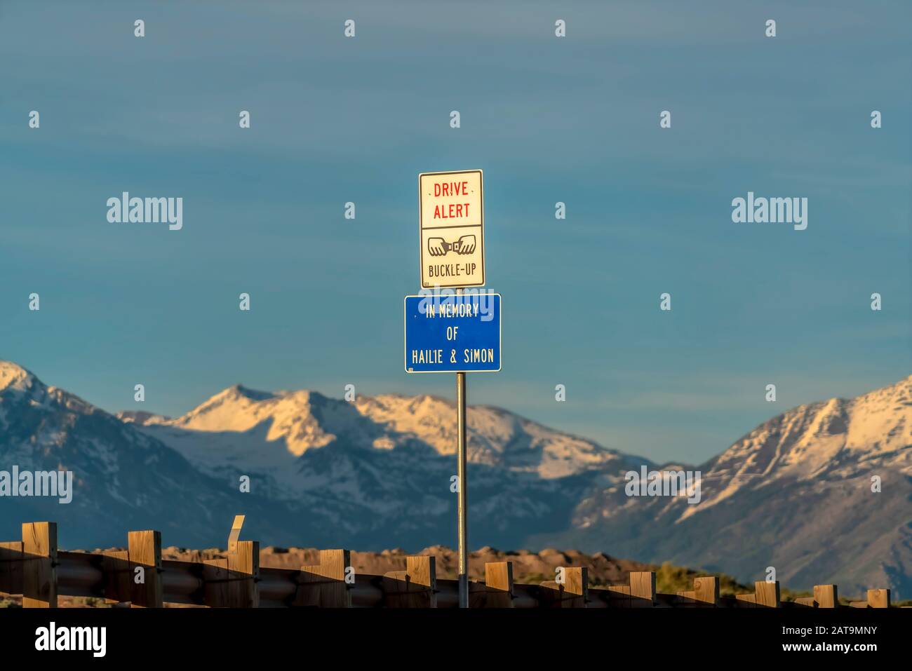 Drive Alert and Buckle Up road sign against snowy mountain and cloudy ...