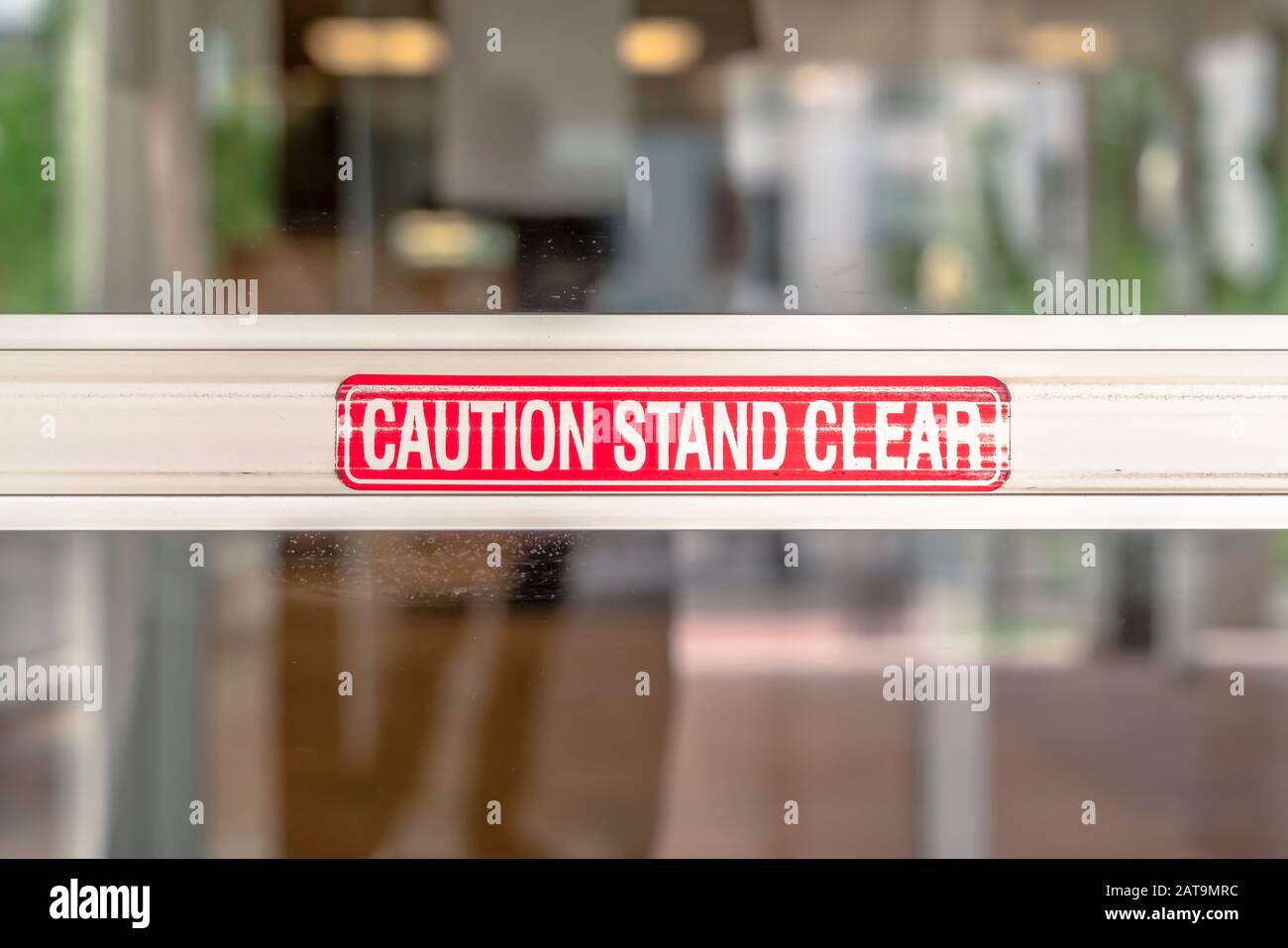 Caution Stand Clear sign on the metal plate of the glass door of a ...