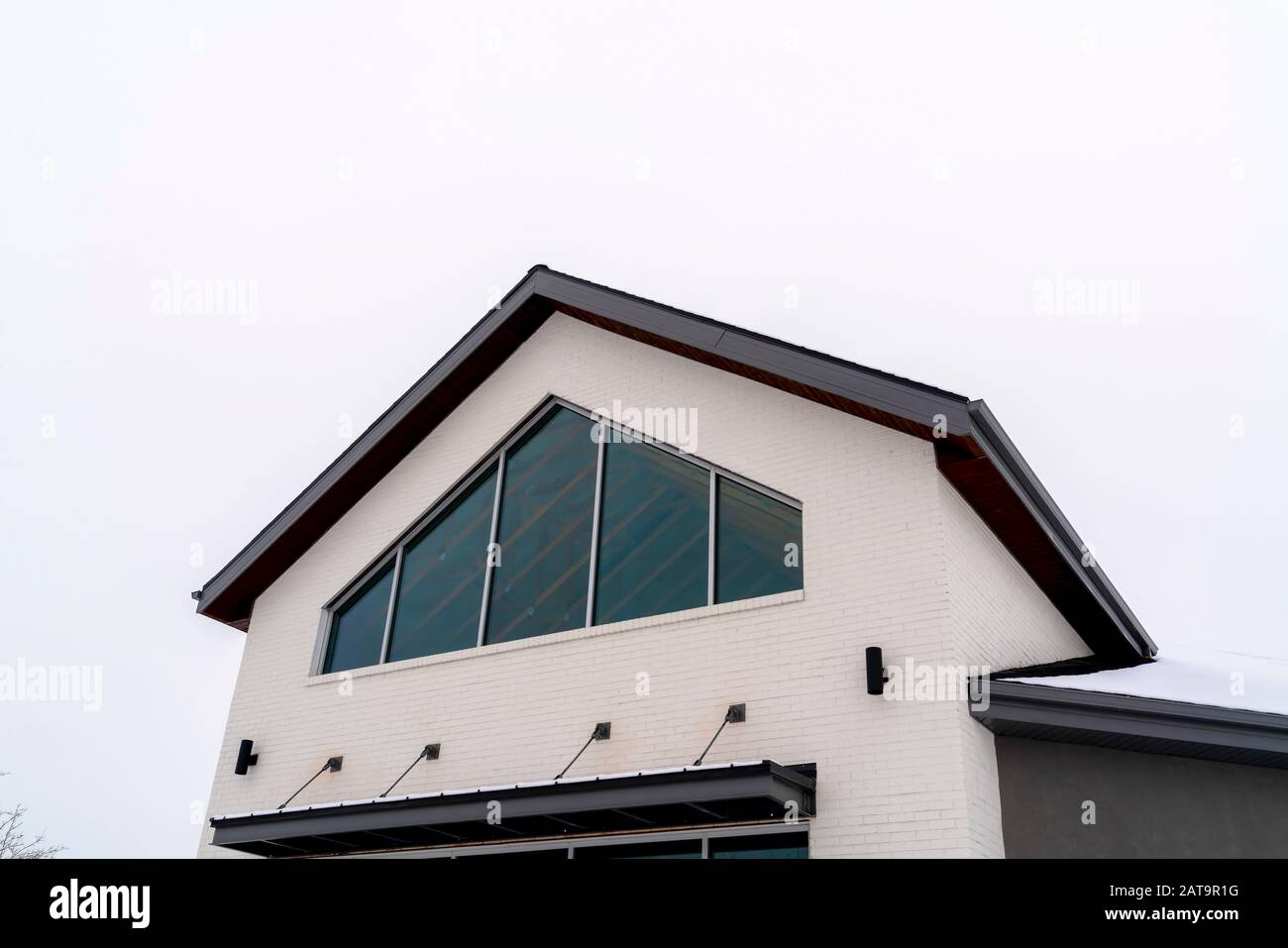 Home exterior with tringular window and white wall under gable roof ...